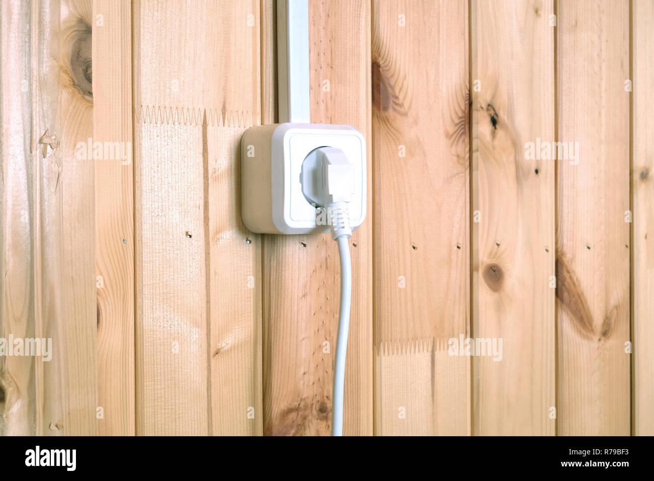 White electric plug in socket on wooden wall with vertical planks side ...