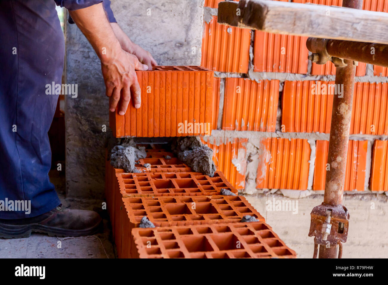 Mason, bricklayer worker is using red blocks to mount a wall at ...