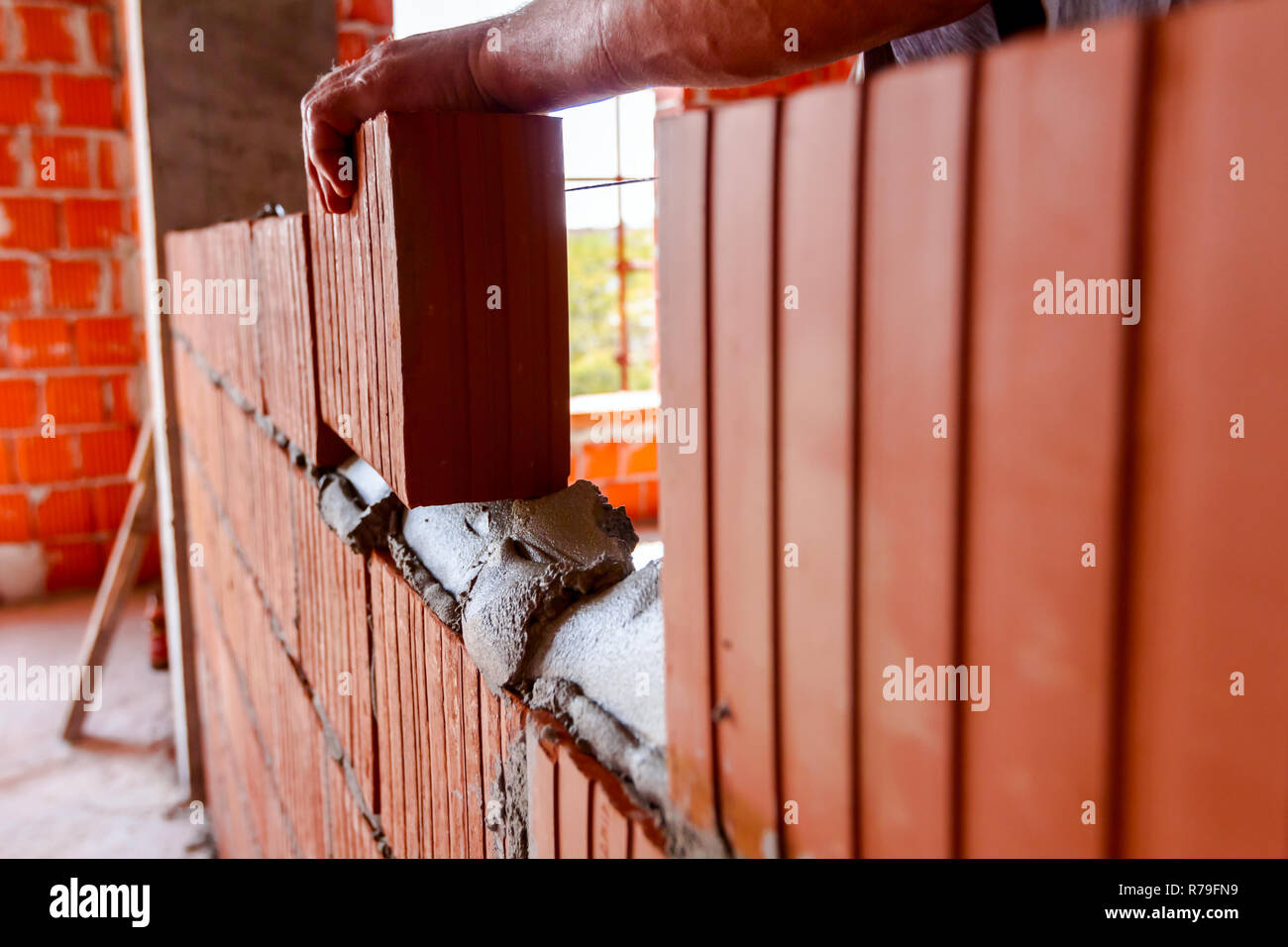 Mason, bricklayer worker is using red blocks to mount a wall at ...