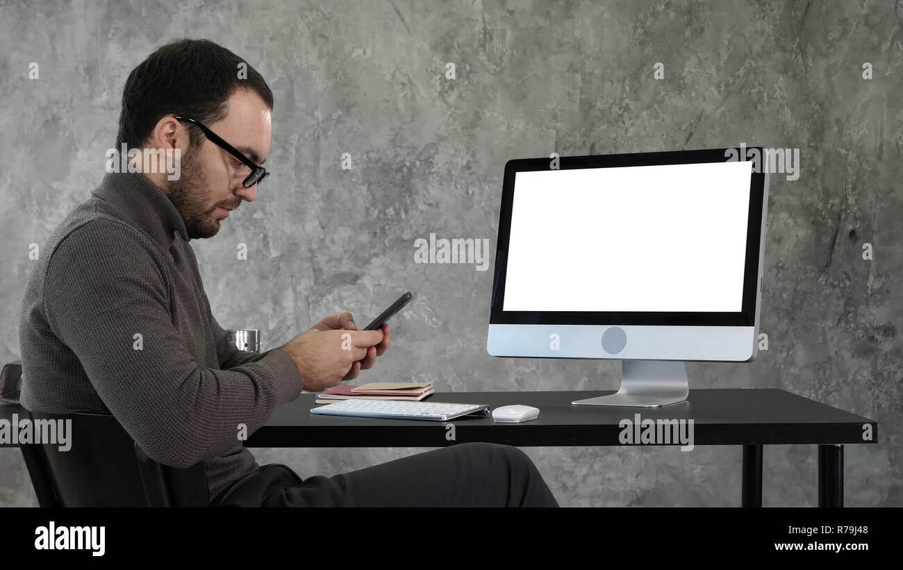 Businessman looking at his smartphone messaging and sitting near ...