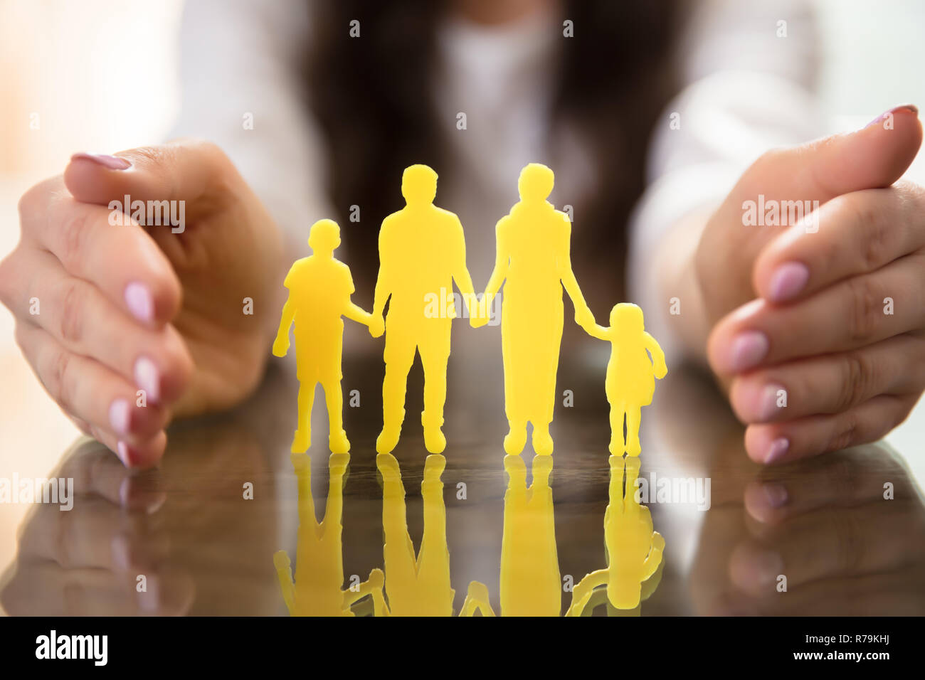 Businesswoman Protecting Family Figures Stock Photo - Alamy
