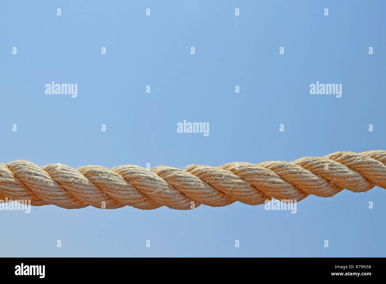 Rustic curved sea rope hanging on blue sky background, Beige cotton for ...