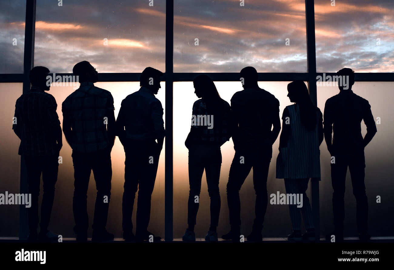 business team talking standing near a large window Stock Photo - Alamy