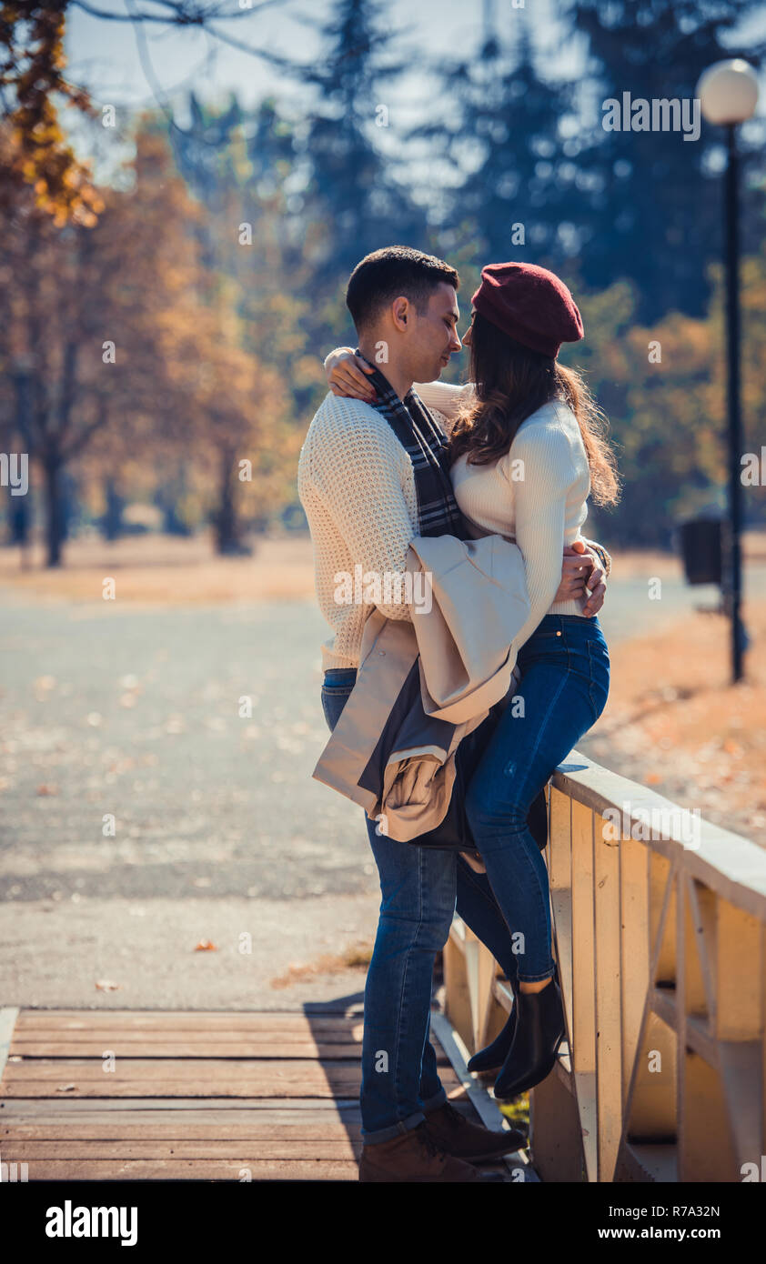 Romantic couple is standing close to each other in the park, hugging and kissing in the park ...