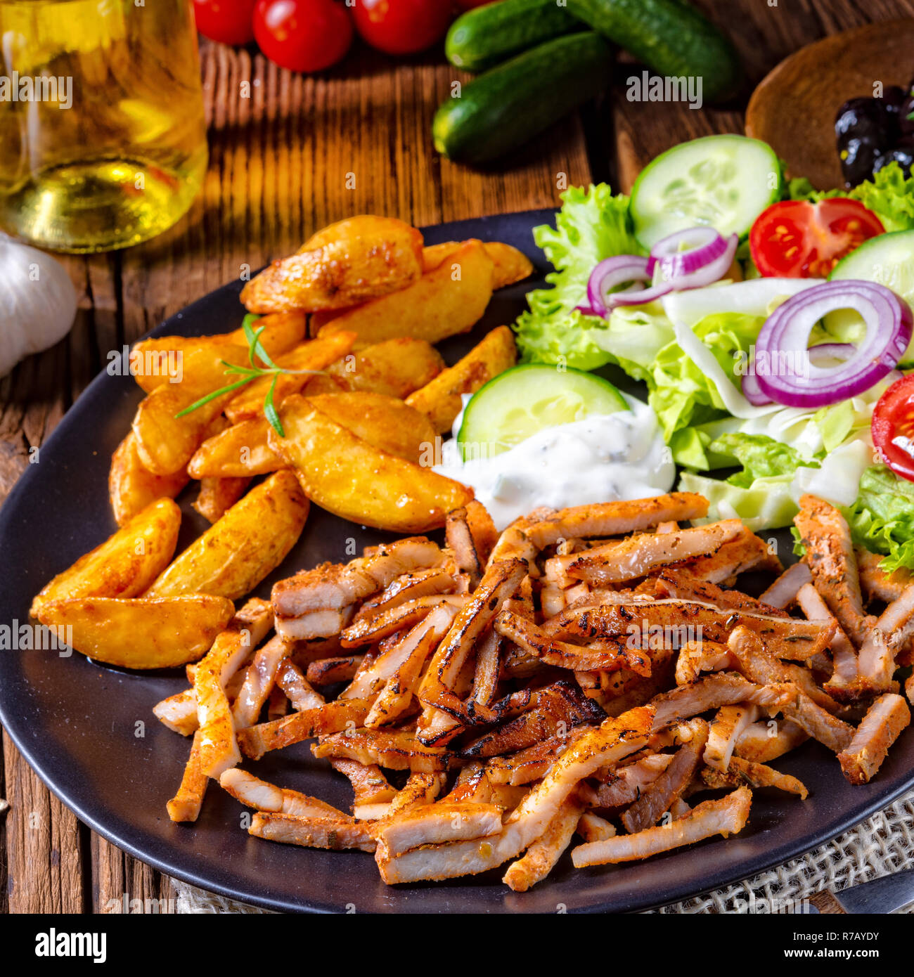 rustic gyros plate with green salad and potato wedges Stock Photo - Alamy