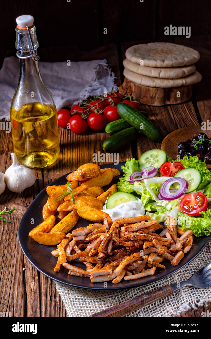 rustic gyros plate with green salad and potato wedges Stock Photo - Alamy