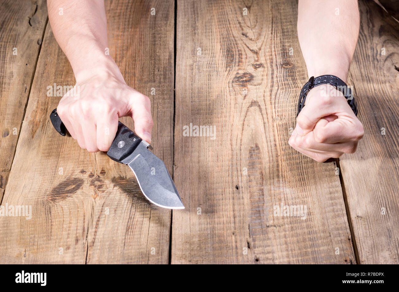 Large folding knife in hand. Hands and a knife. Wooden background Stock ...