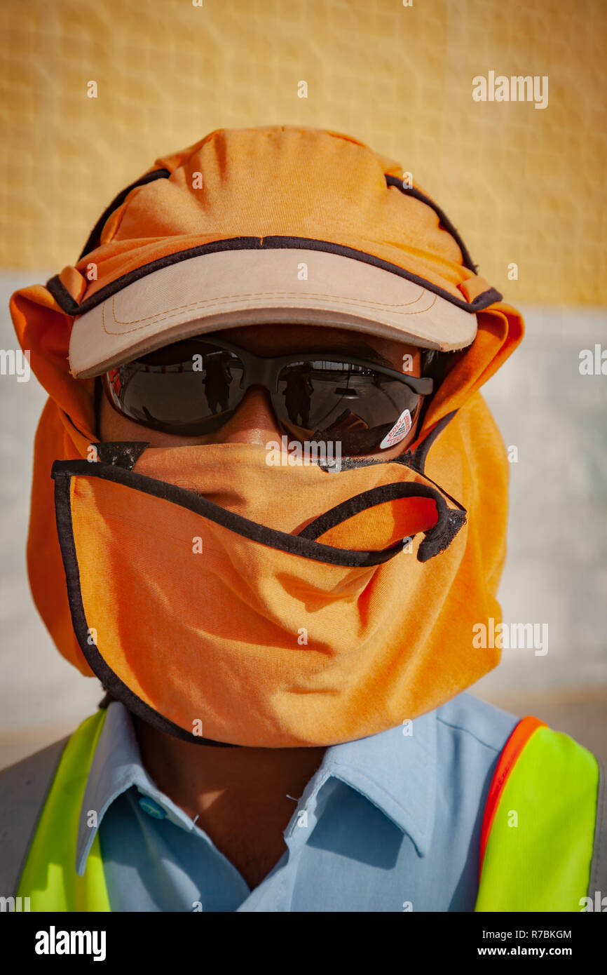 Worker wearing sunglasses with hats and head covering on a construction ...