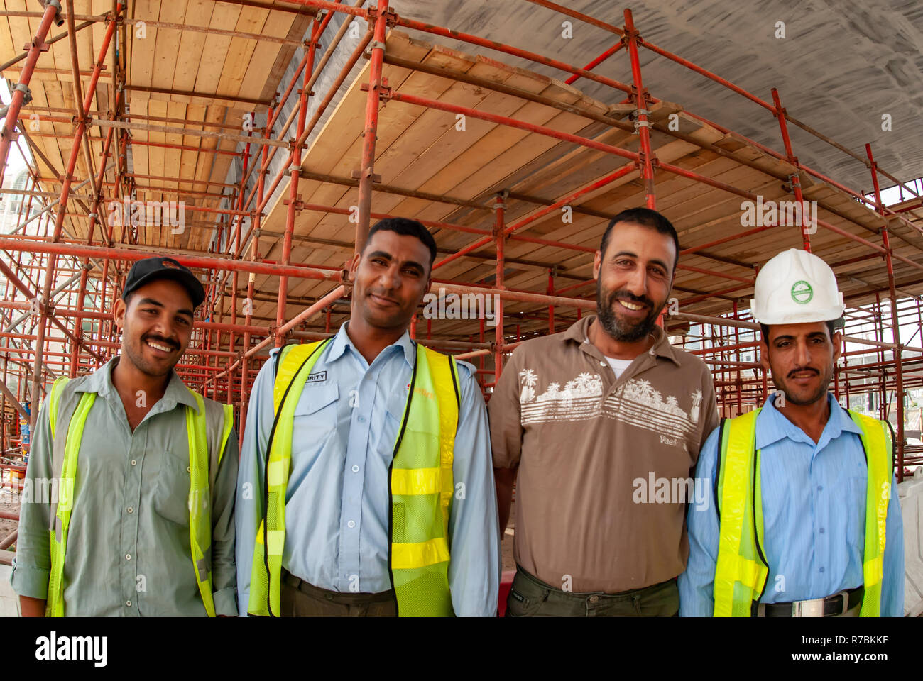 4 happy construction workers relax during a break on a building site in ...