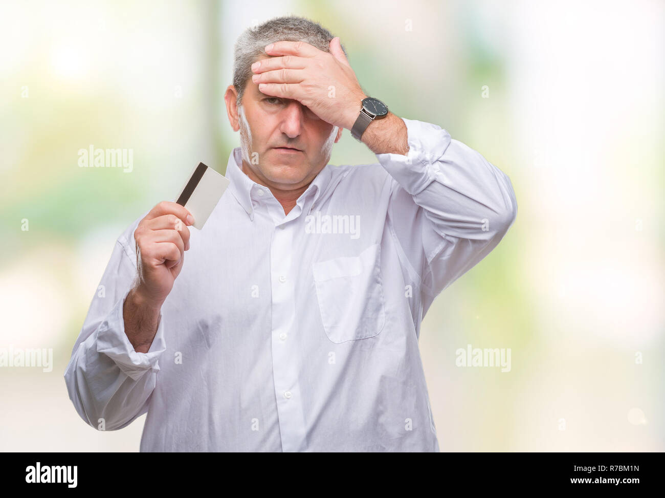 Handsome senior man holding credit card over isolated background ...