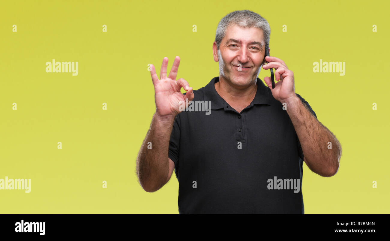 Handsome senior man talking on smartphone over isolated background ...