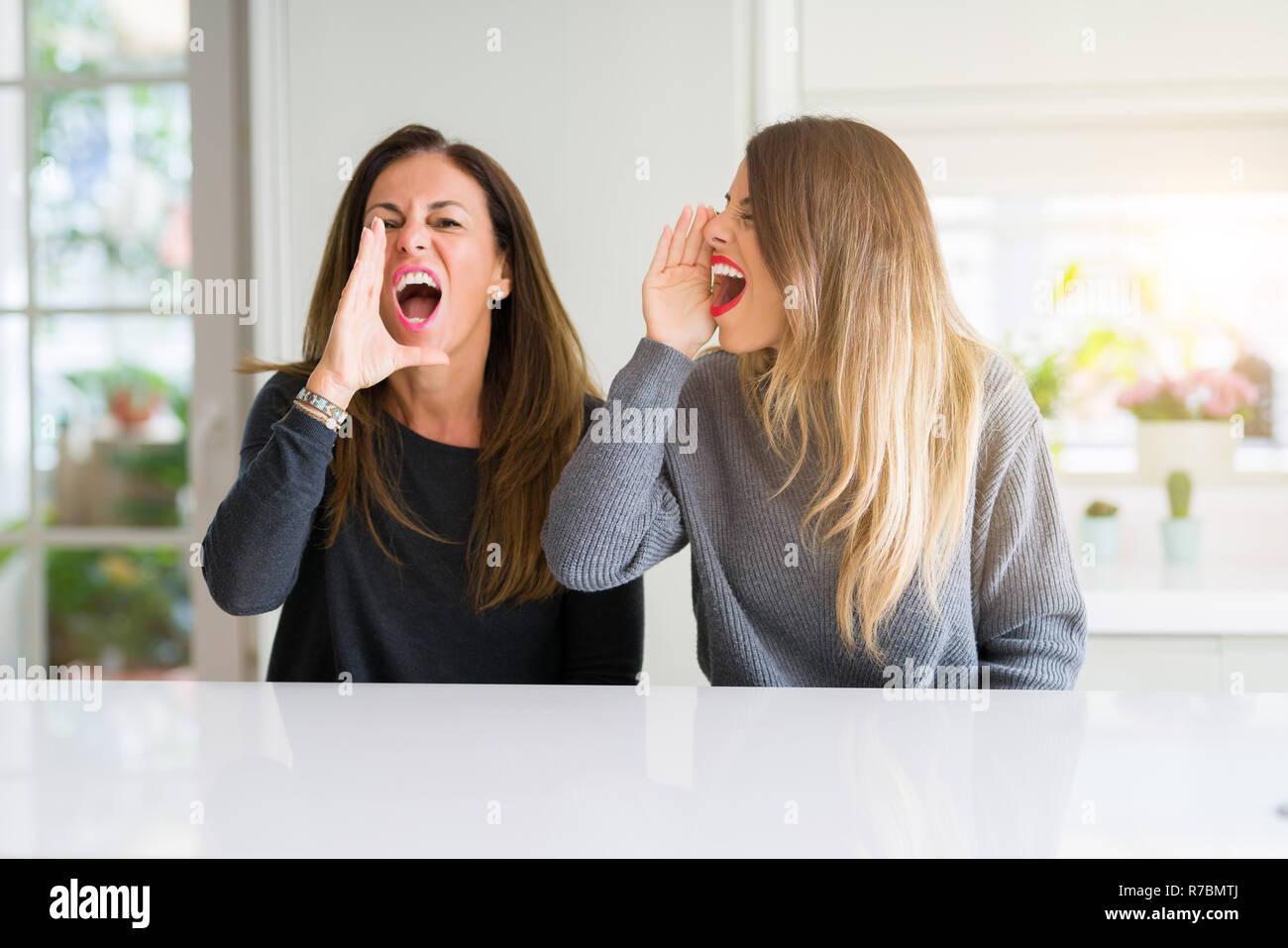 Beautiful family of mother and daughter together at home shouting and ...