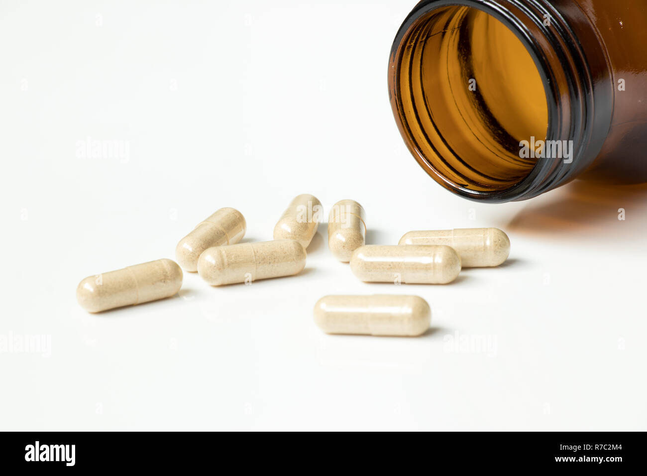 Transparent hard capsule with brown powder and amber glass bottle on ...