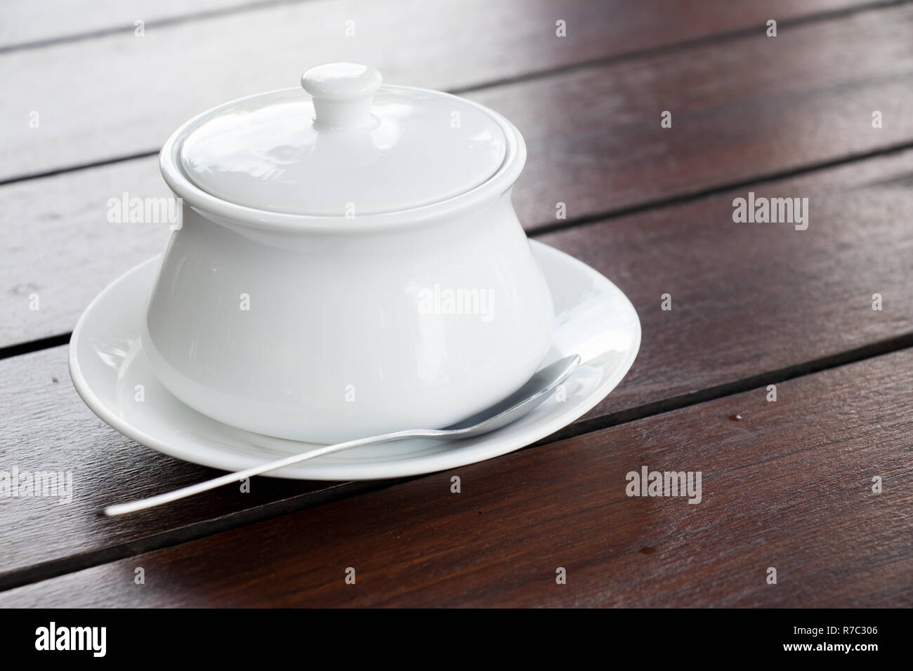 White ceramic container contain the seasoning on wood table background ...