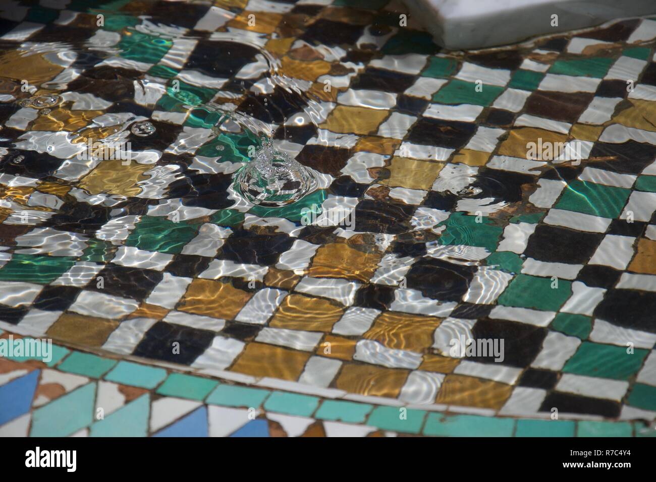 Water dramatically forms droplets and ripples in a tiled African ...