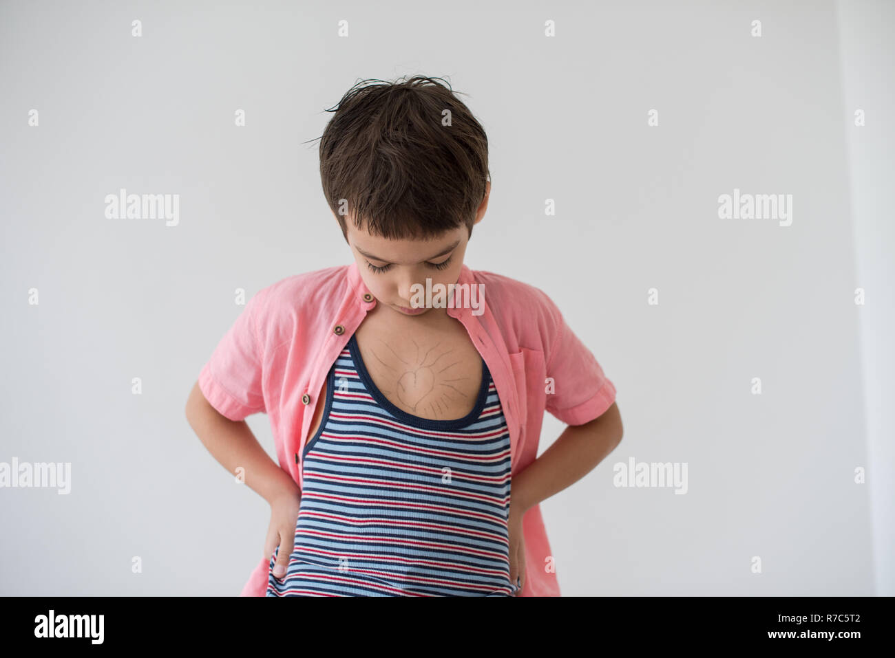 happy little boy looking at heart love symbol sketched on his chest ...