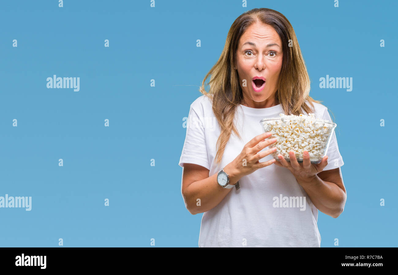 Middle age hispanic woman eating popcorn over isolated background ...