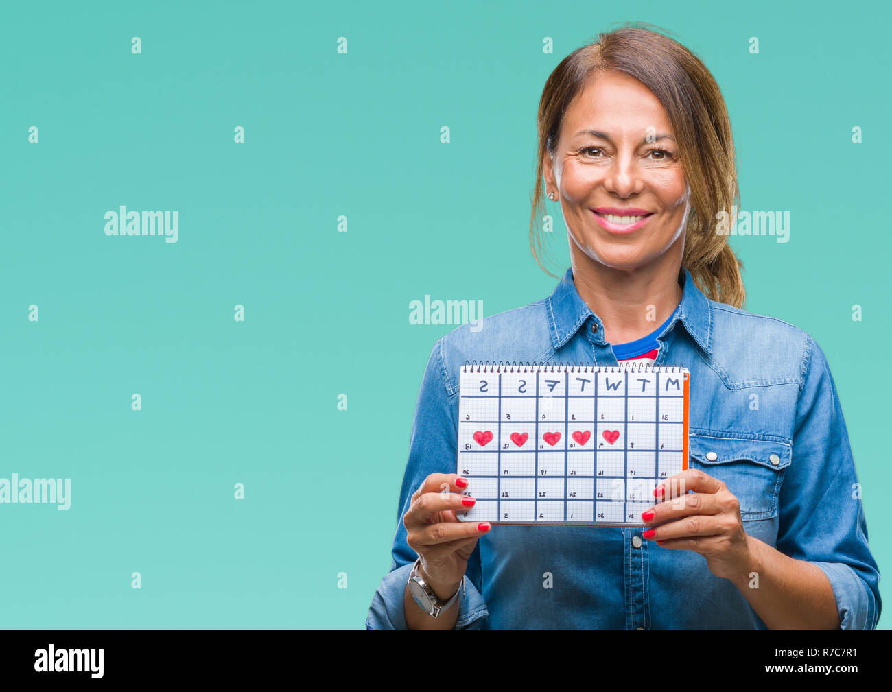 Middle age senior hispanic woman holding menstruation calendar over ...