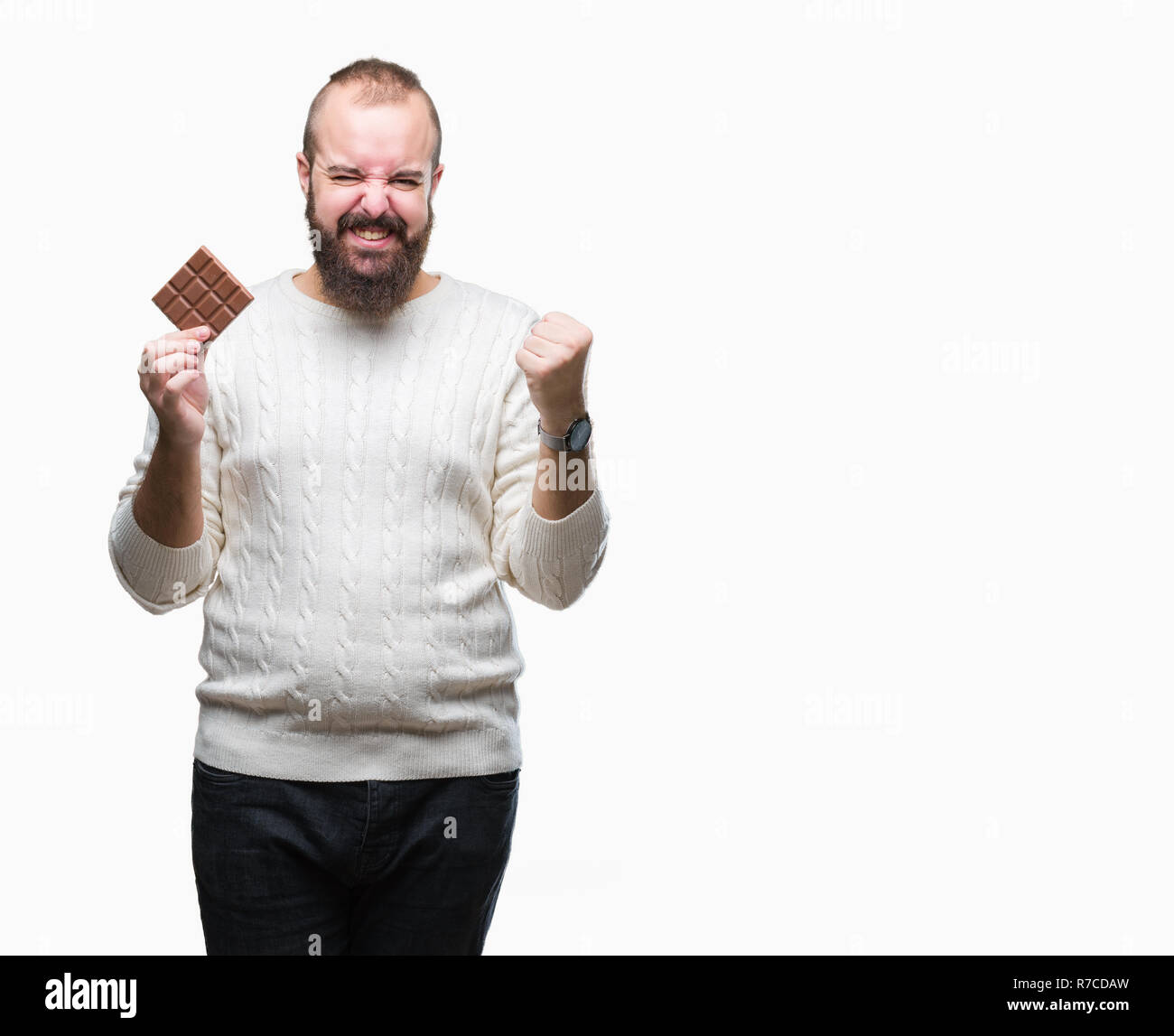 Young hipster man eating chocolate bar over isolated background ...