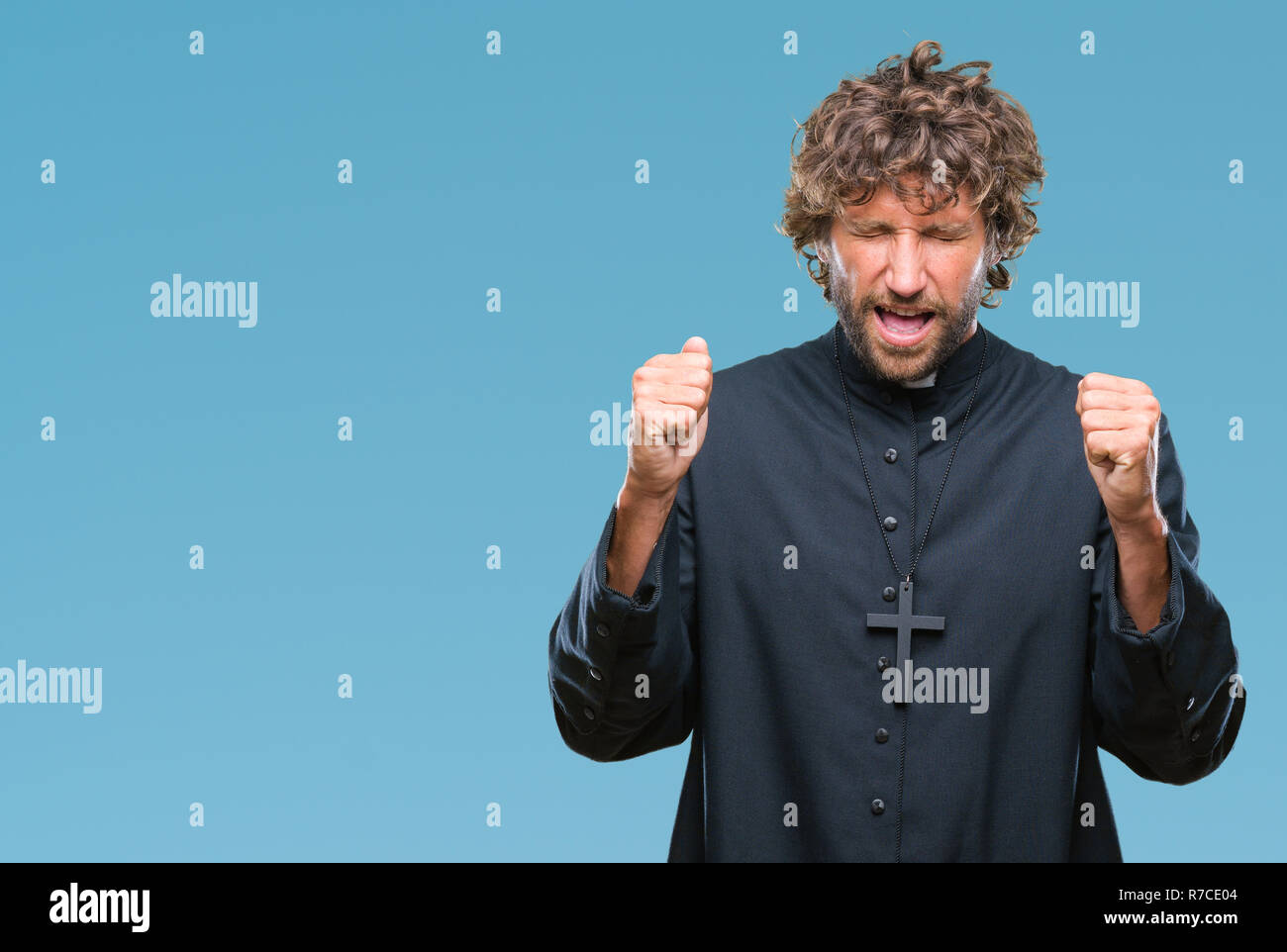 Handsome hispanic catholic priest man over isolated background excited ...