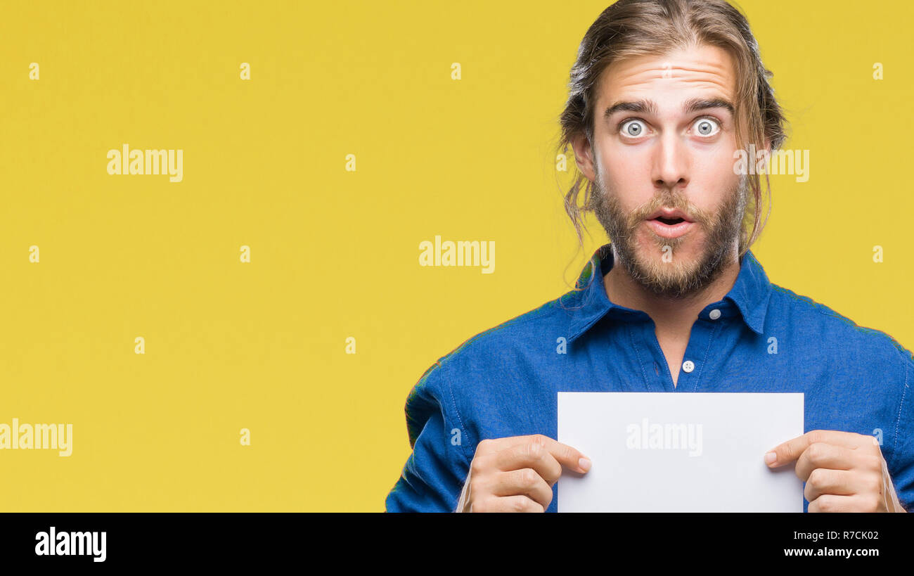 Young handsome man with long hair over isolated background holding ...