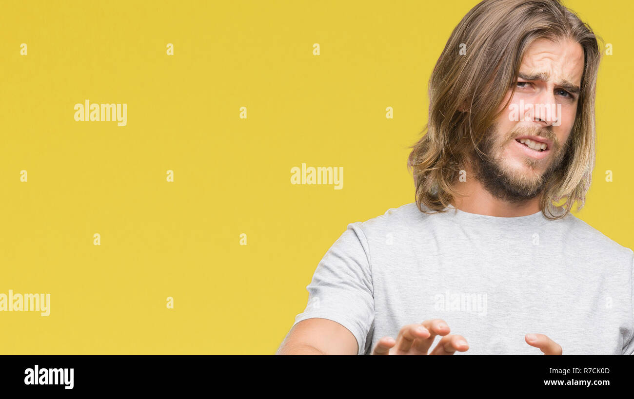 Young handsome man with long hair over isolated background disgusted ...