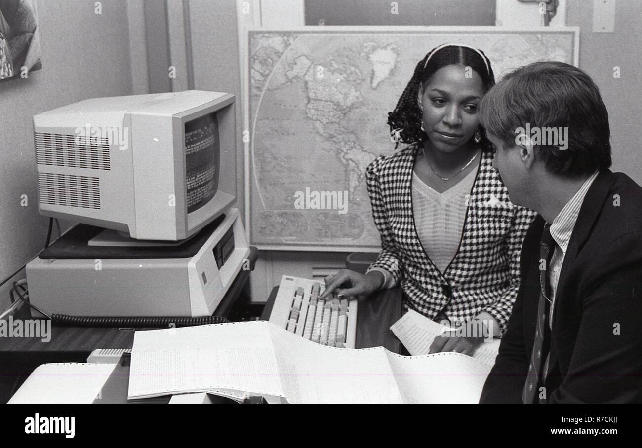 Man and woman talking to each other; near a computer desk Stock Photo ...