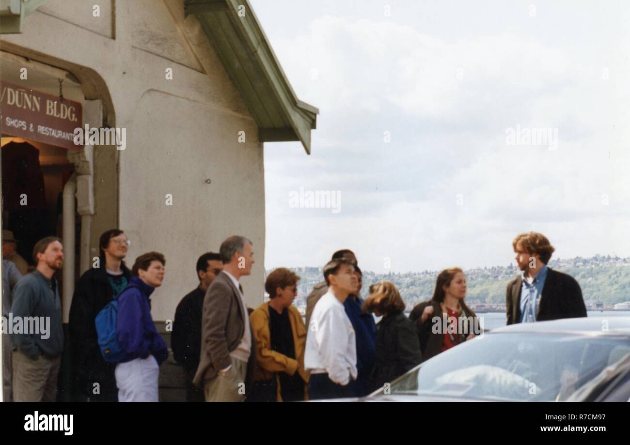 A GROUP OF MEN AND WOMEN ARE HAVING A CONVERSATION IN A MARKET PLACE ...