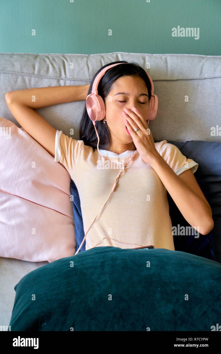 Beautiful woman posing - lying down, listening music, relaxing, sleepy and yawning Stock Photo ...