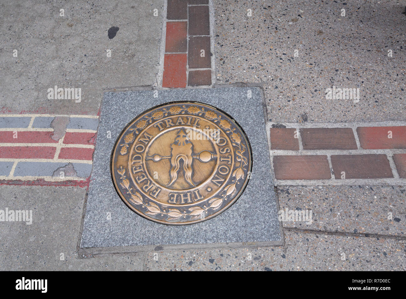 A brick line and brass medallion in the pavement marking the historic ...