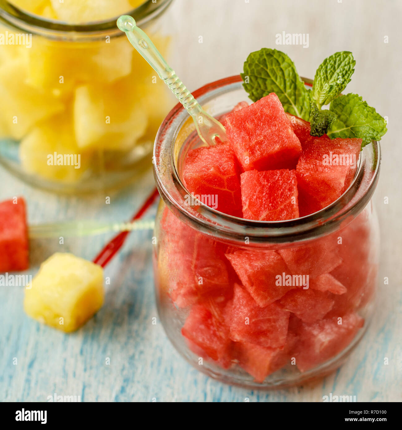 Cut cubes of red and yellow watermelon in glass jars with mint and ...