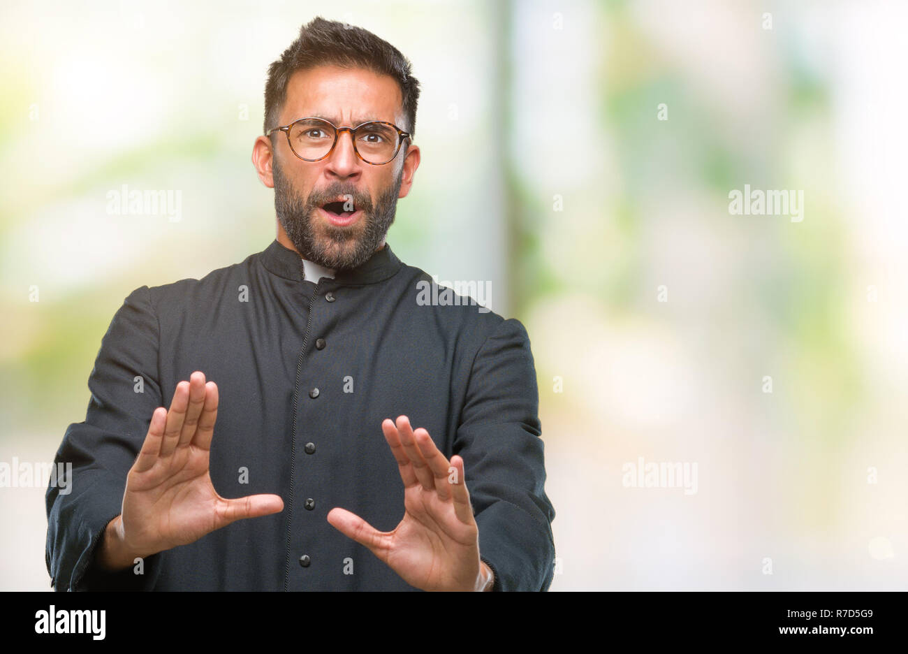 Adult hispanic catholic priest man over isolated background afraid and ...
