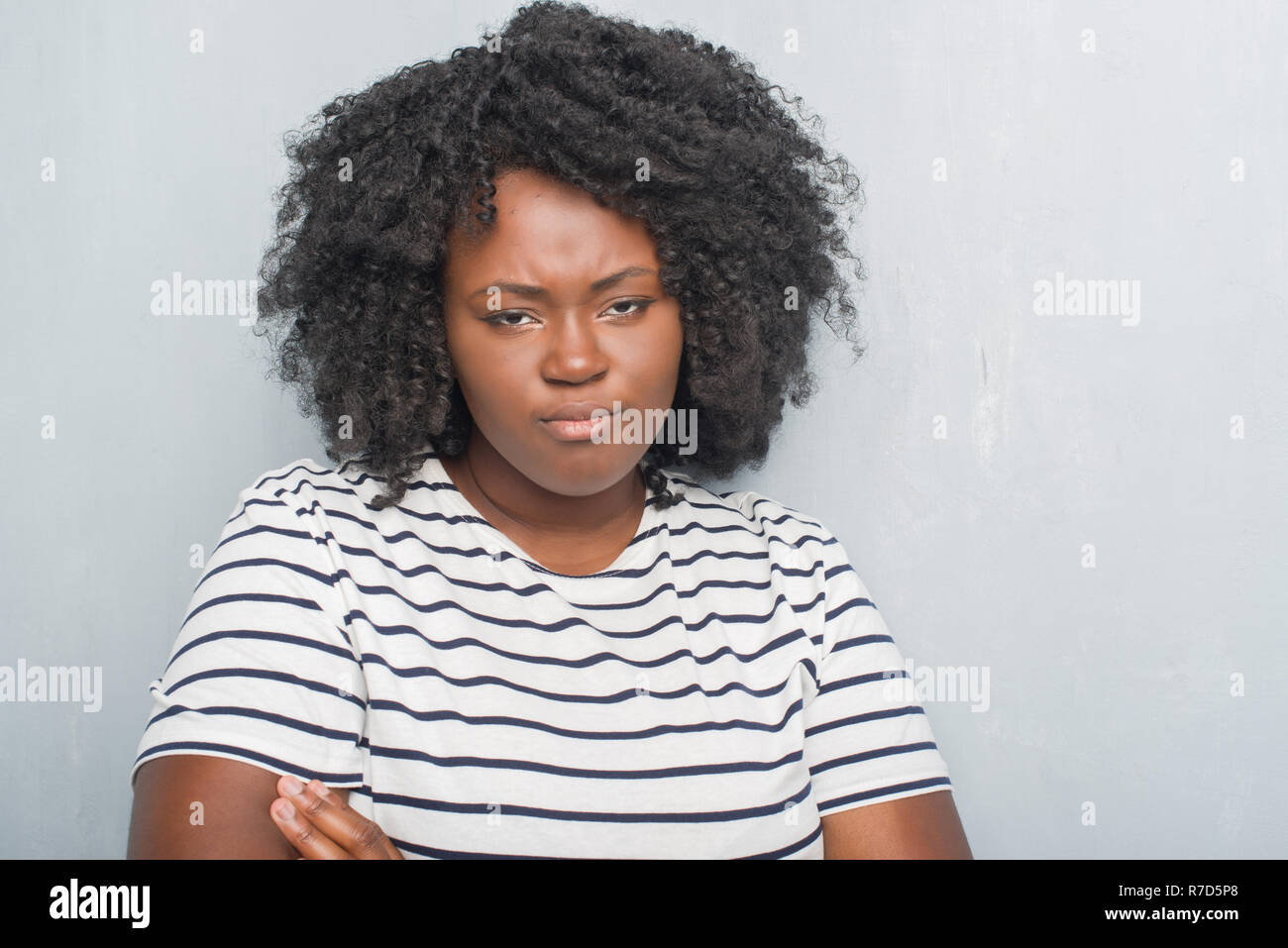 Young african american plus size woman over grey grunge wall skeptic ...