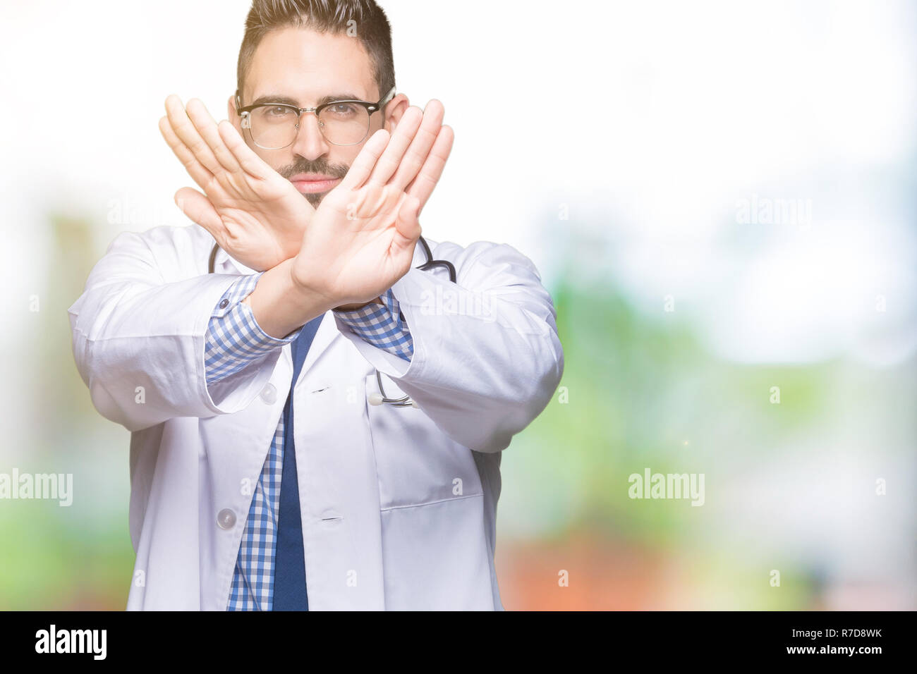 Handsome young doctor man over isolated background Rejection expression ...