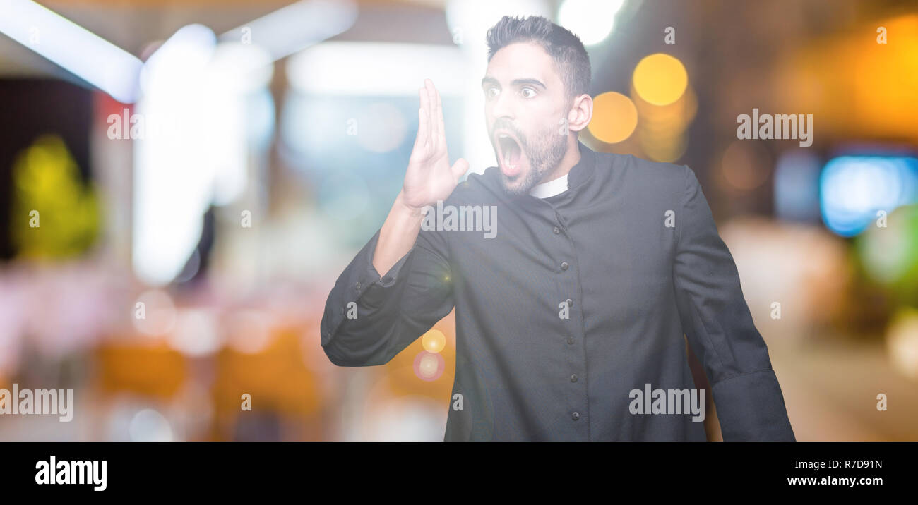 Young Christian priest over isolated background shouting and screaming ...