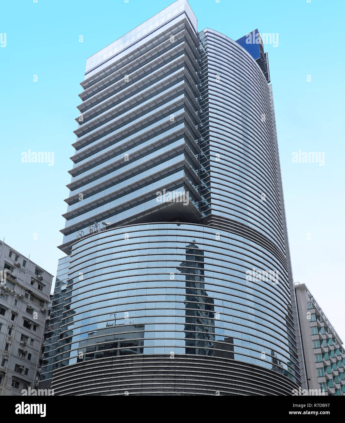 Modern tall skyscraper with glass facade and smaller buildings in the ...