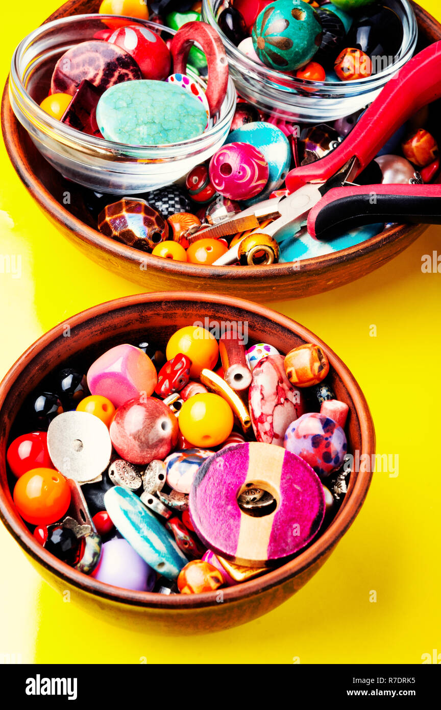 Jewelry making and beading process.Colored beads on yellow background ...