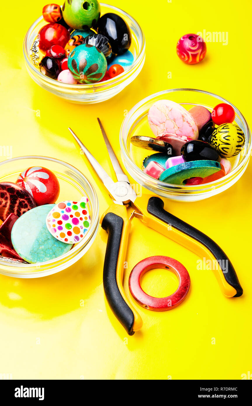 Jewelry making and beading process.Colored beads on yellow background ...