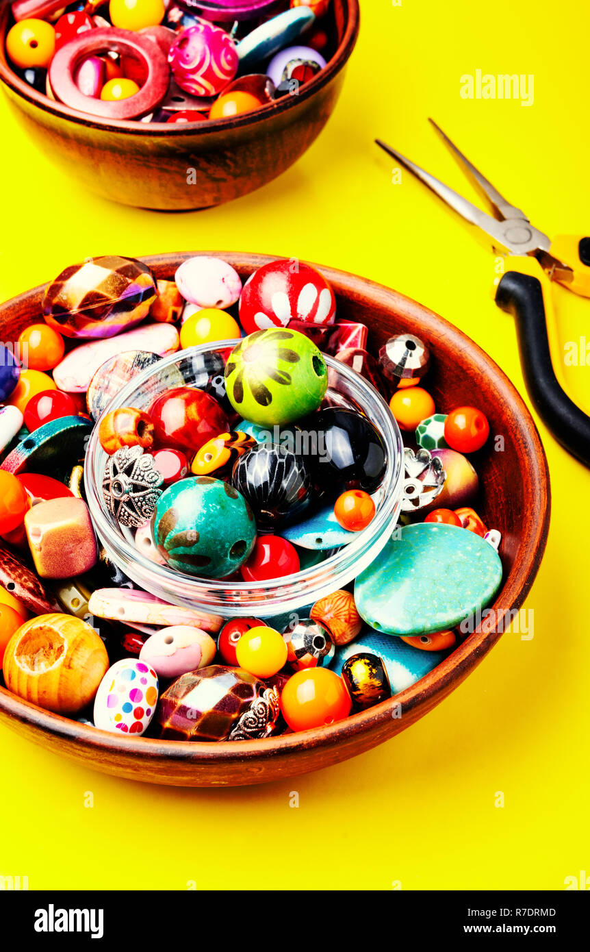 Jewelry making and beading process.Colored beads on yellow background ...