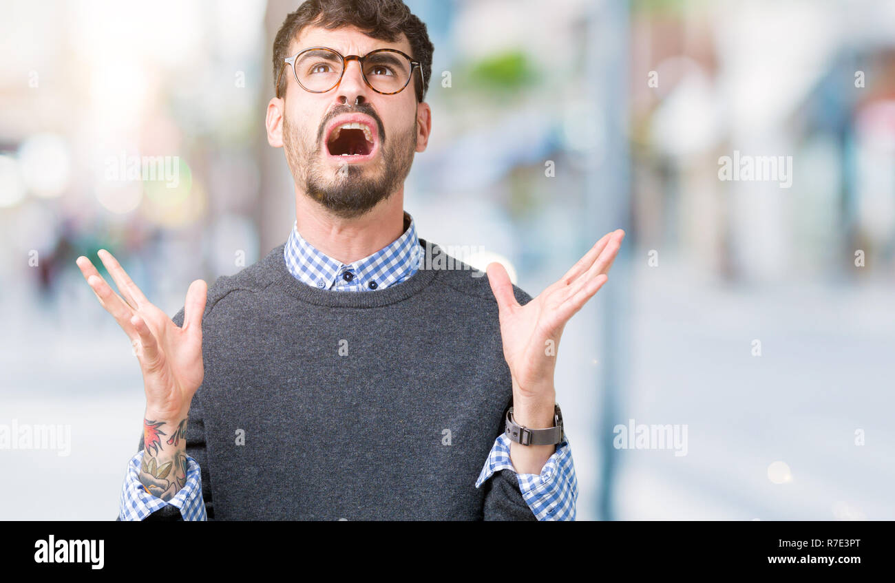Young handsome smart man wearing glasses over isolated background crazy ...