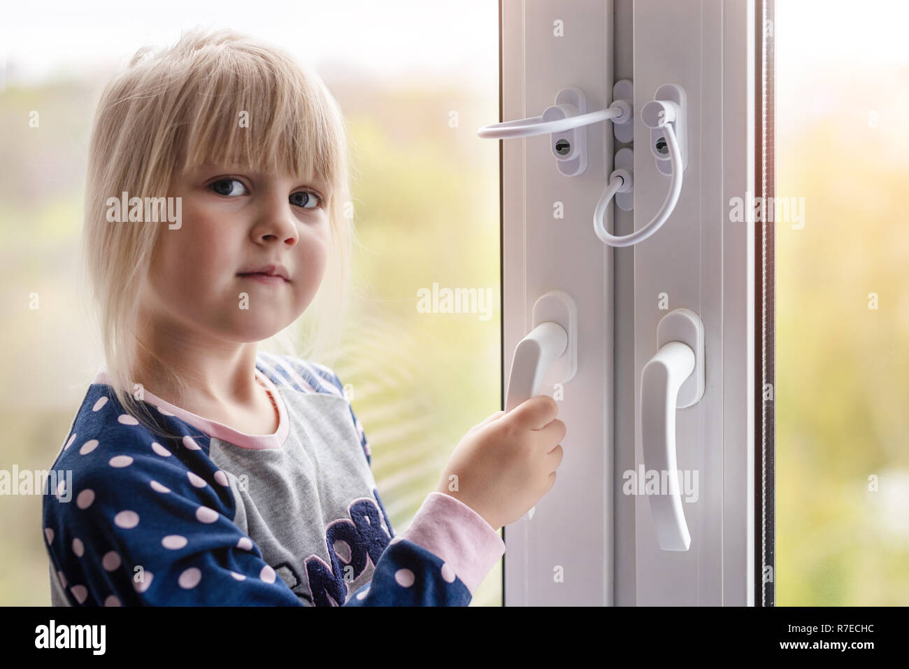 Little cute toddler girl trying to open window in apartment at high ...
