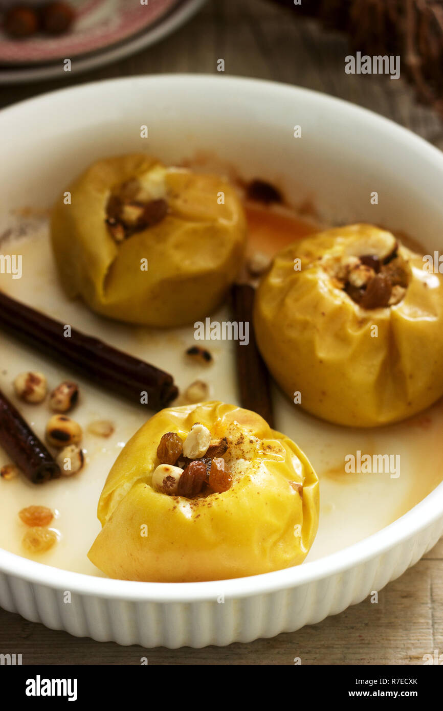 Baked apples with raisins, hazelnuts and cinnamon on wooden background ...
