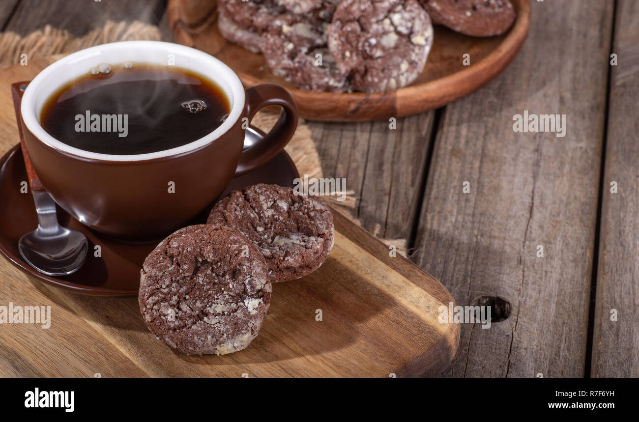 Chocolate fudge cookie and steaming cup of coffee with plate of cookies ...
