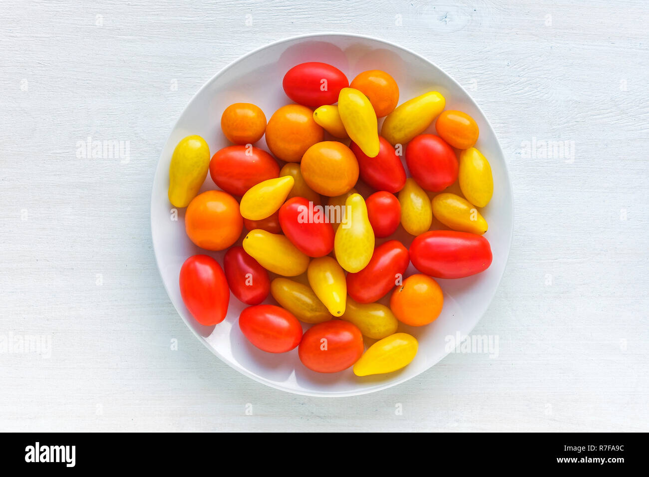 White ceramic plate with yellow and red organic tomatoes, viewed from ...