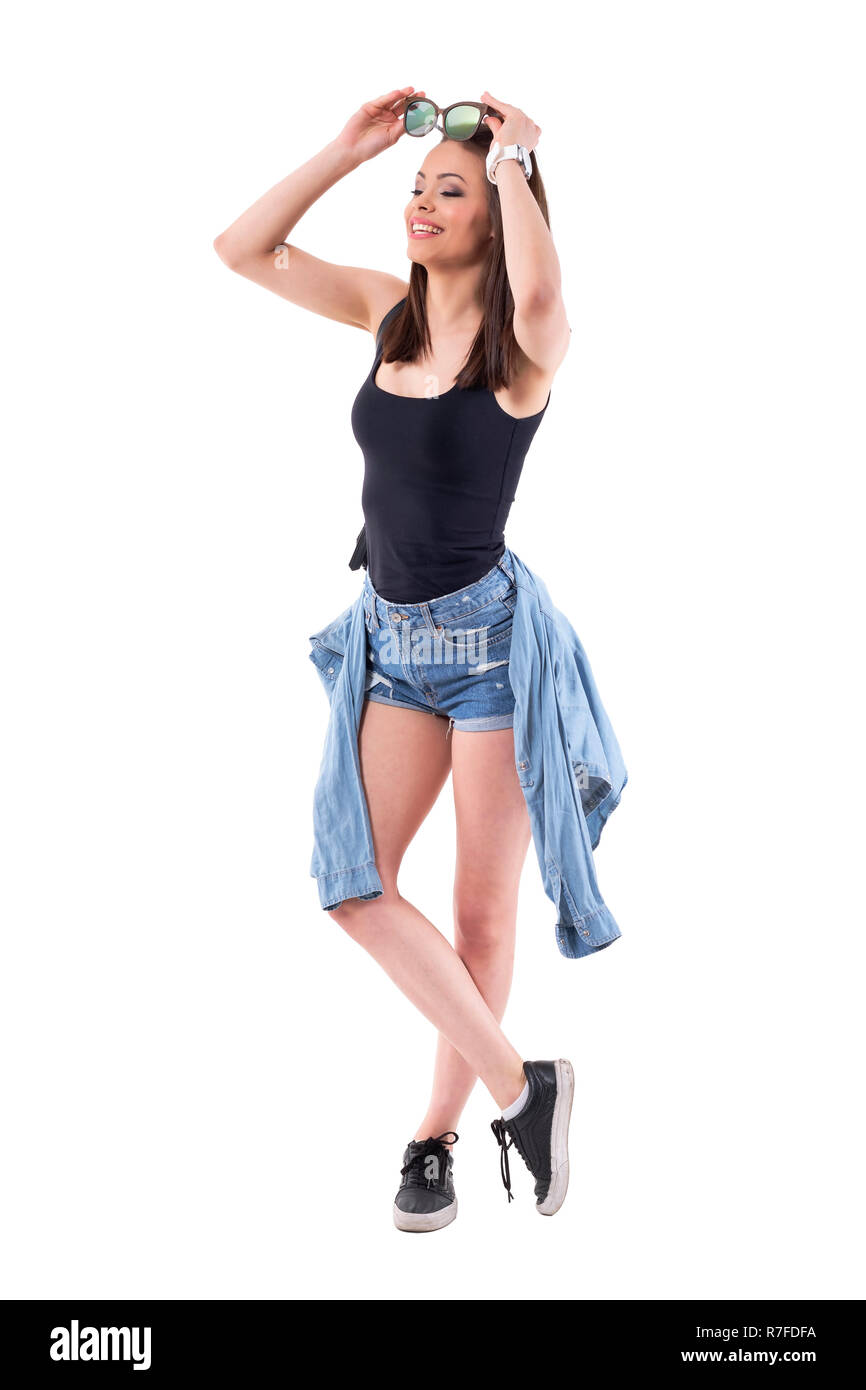 Carefree millennial youth. Young trendy woman putting on sunglasses on ...