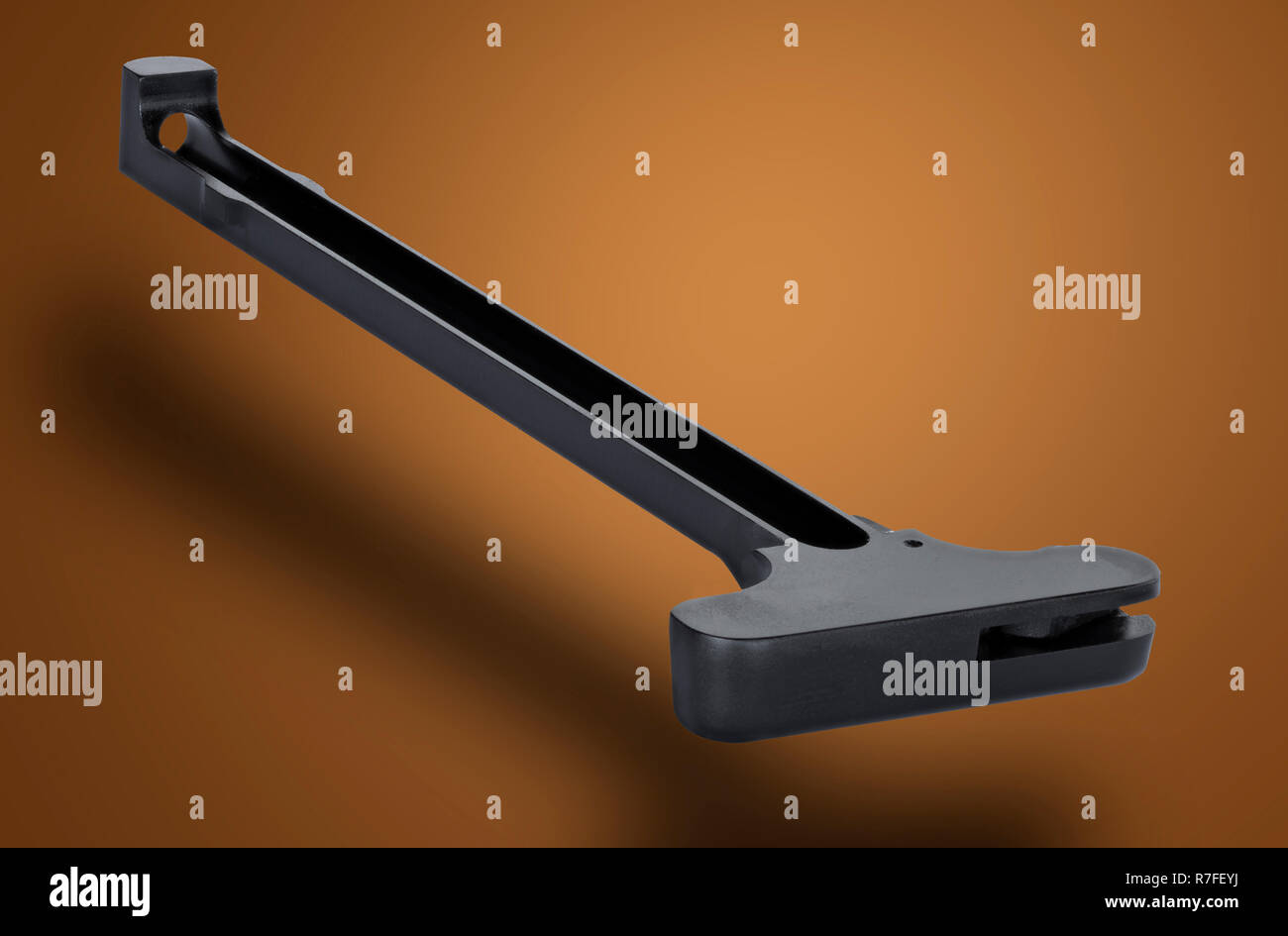 Assault rifle charging handle bottom on a brown background with shadow ...