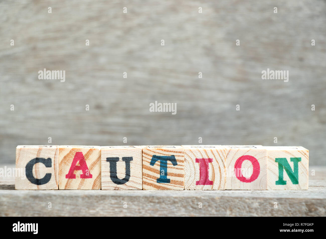 Letter block in word caution on wood background Stock Photo - Alamy