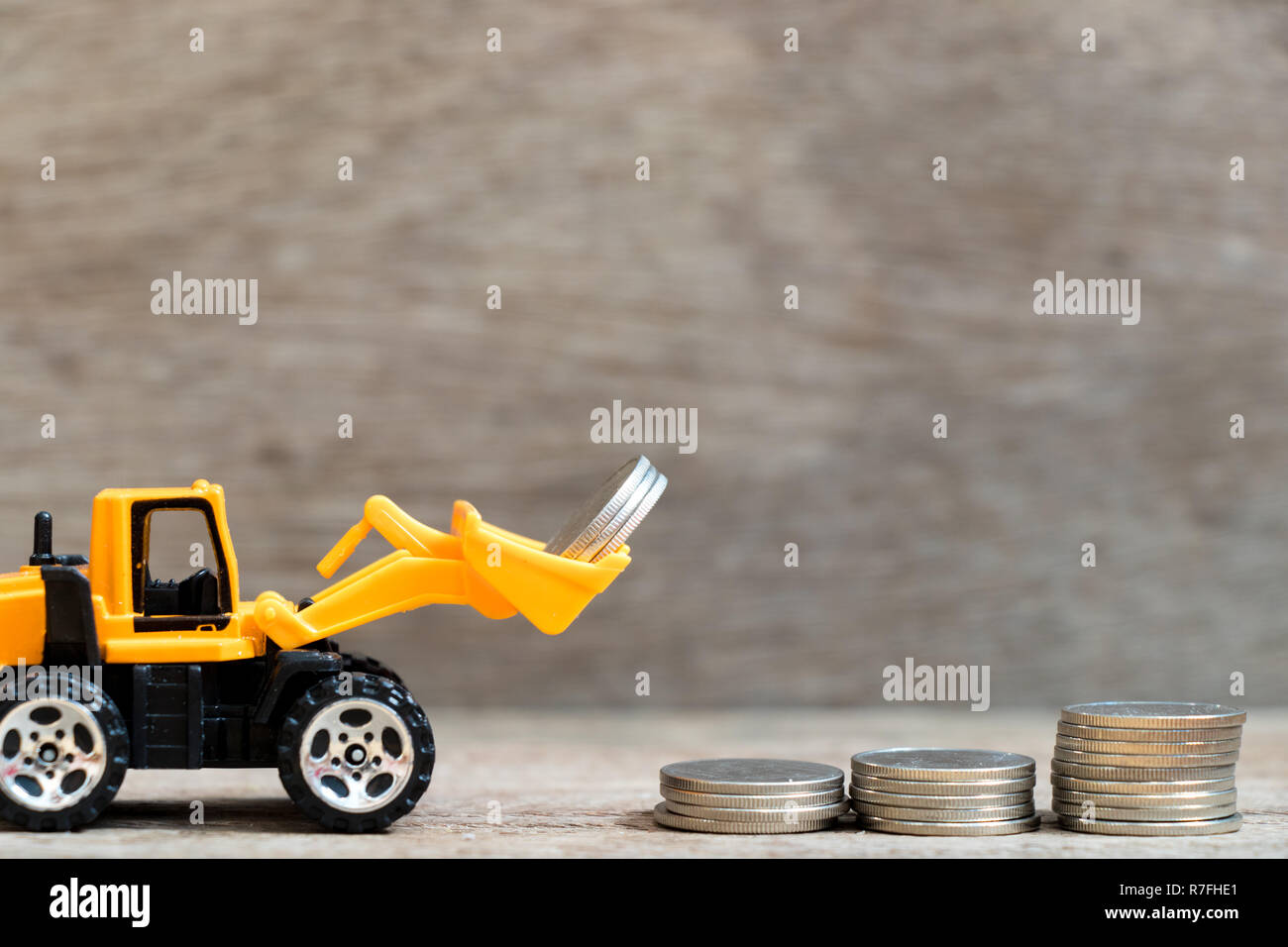 Toy bulldozer hold group of coin to fulfill up trend of stacked coin on ...