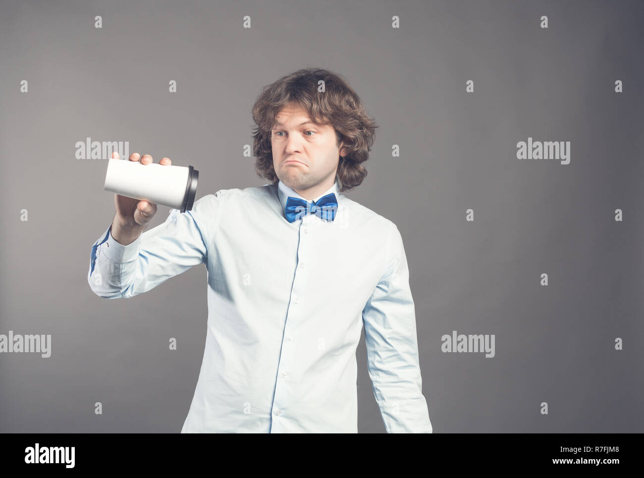 Upset guy with sad expression holding disposable paper cup of coffee ...