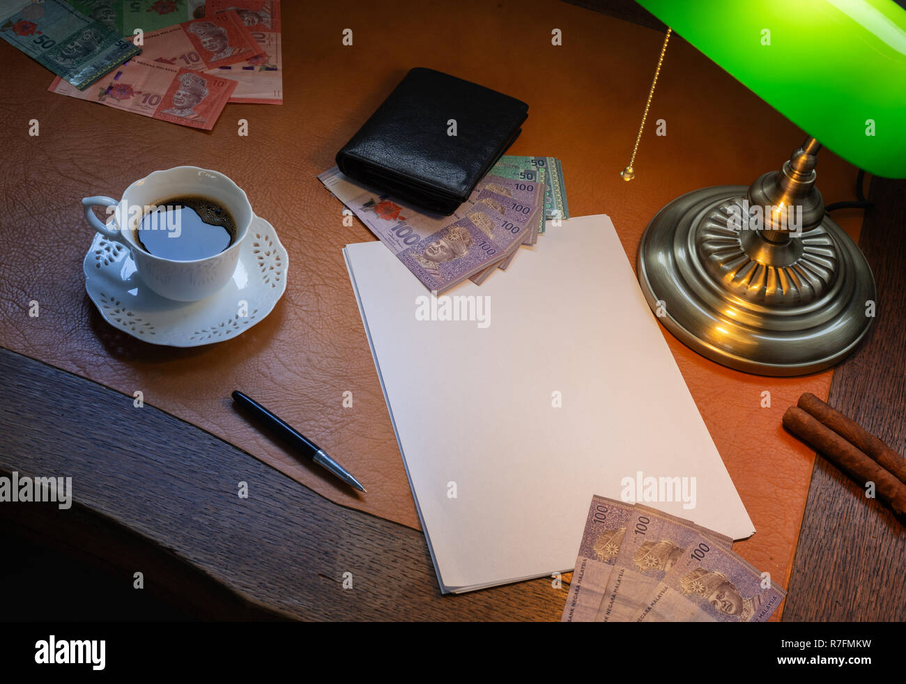 Malaysian money, Ringgit, on a stylish desk lit with a banking lamp ...